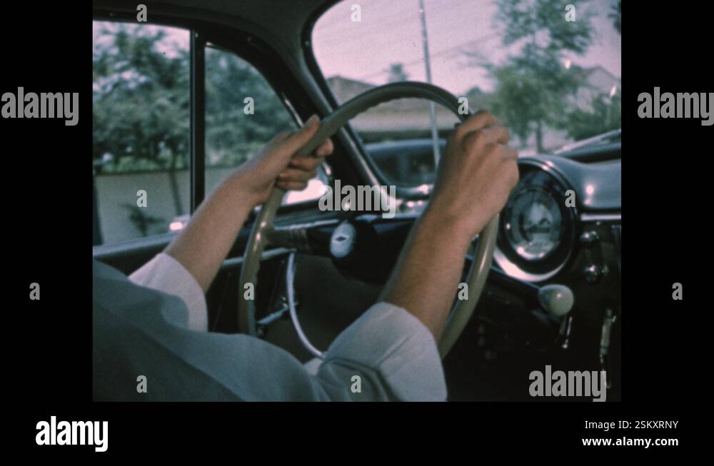 1950s: Young man drives. Hand holds shooting slate. Young man signals ...