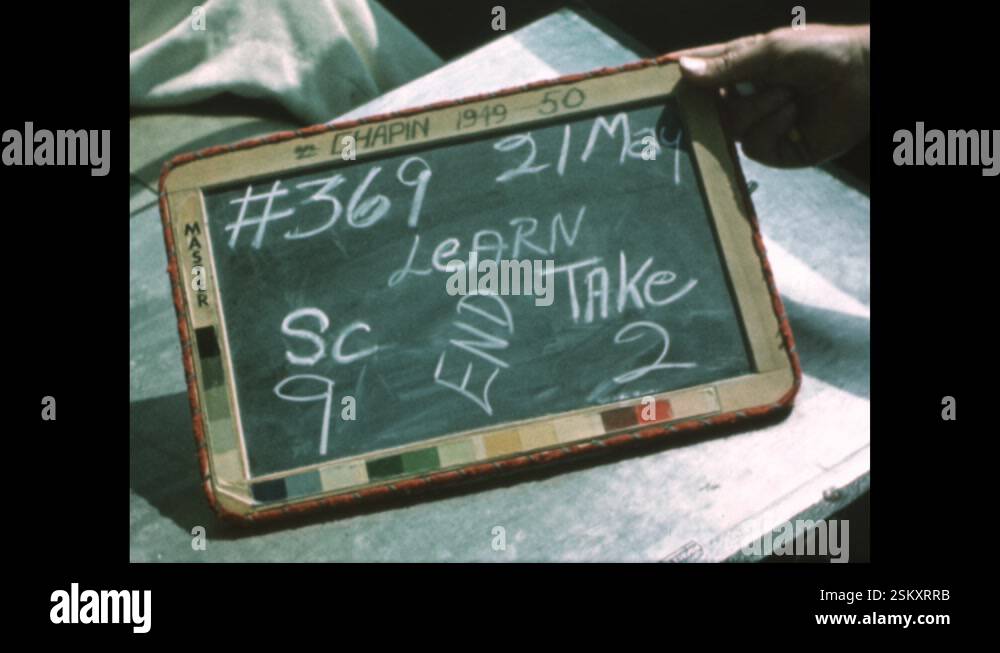 1950s: Boy on bike passes car. Hand holds shooting slate. Father and ...