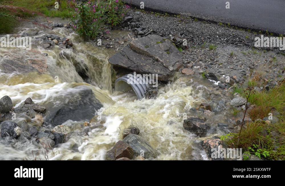 Rainwater rushes into culvert running under road during flooding in ...