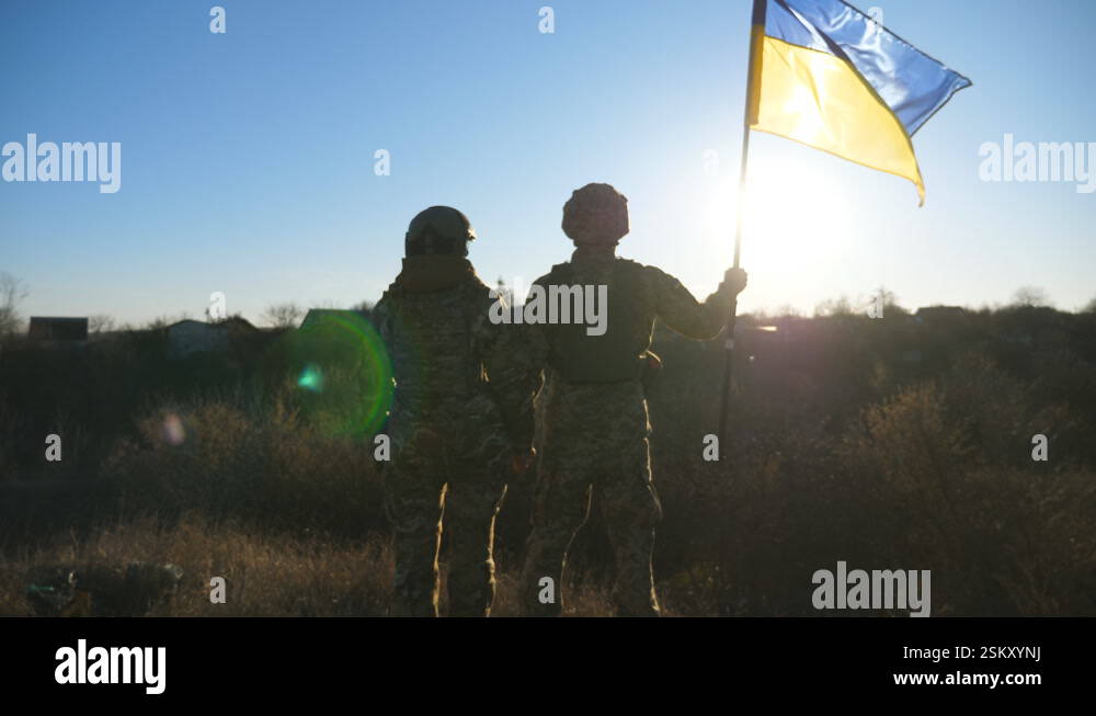 Soldier of ukrainian army standing at peak of hill with raised flag of ...