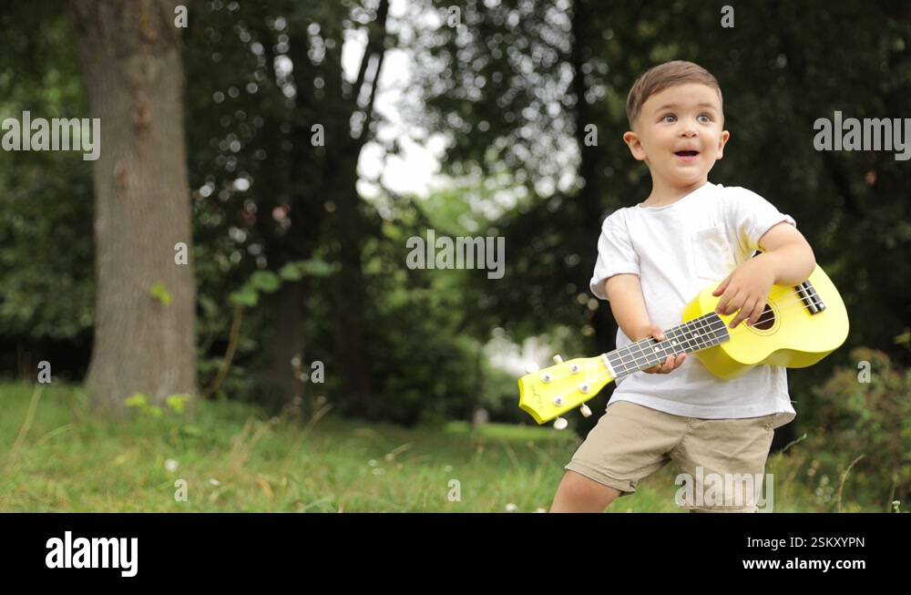Handsome boy playing music in the park on the ukulele, the concept of ...