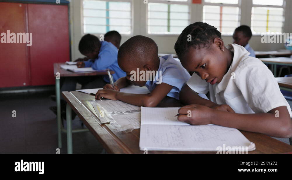 Close-up. Black African school children drawing at a desk in a ...