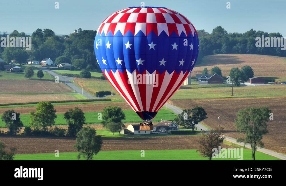 Drone orbits around an American flag hot air balloon above farmland of ...