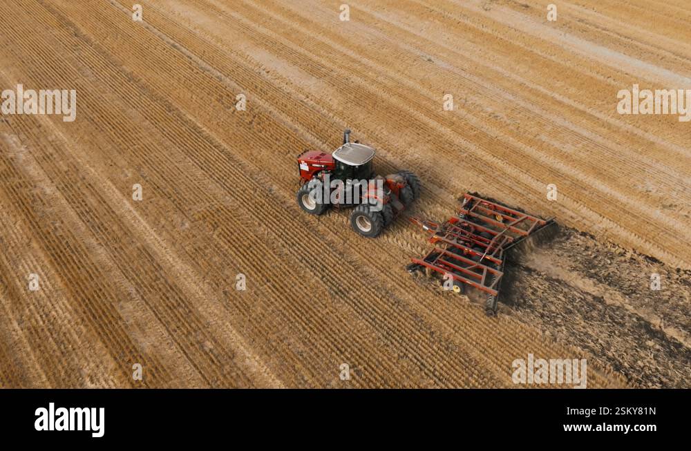 Big red Tractor Pulling Disc Harrow Through Field in Preparation soil ...