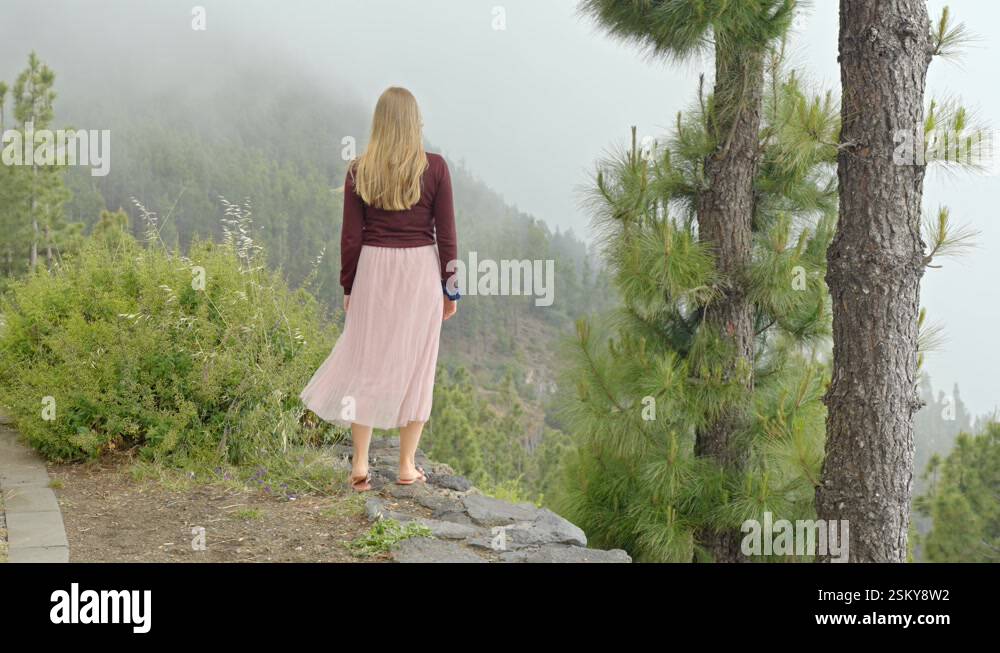 Pretty woman walks along rocky overlook at top of mountain in teide ...