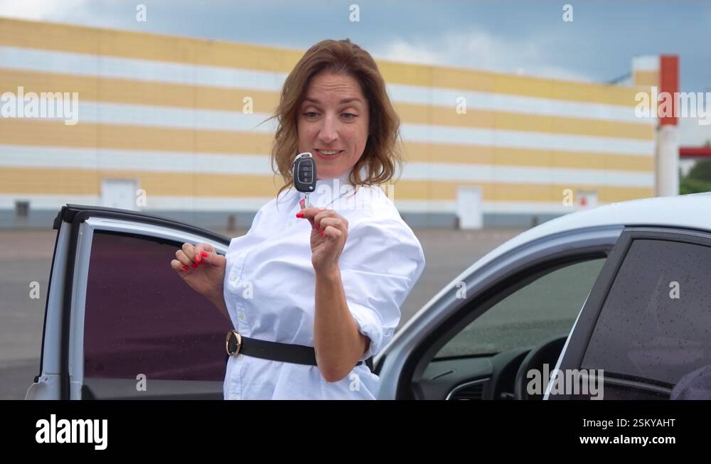 Woman showing key with surprised emotion stand near just buying white ...