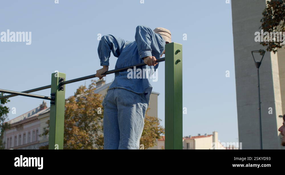 Young man engaging in physical activity, performing pull-ups on ...