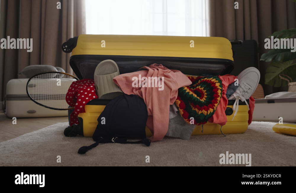 Traveler suitcase full of clothes overflowing things. Open packed ...