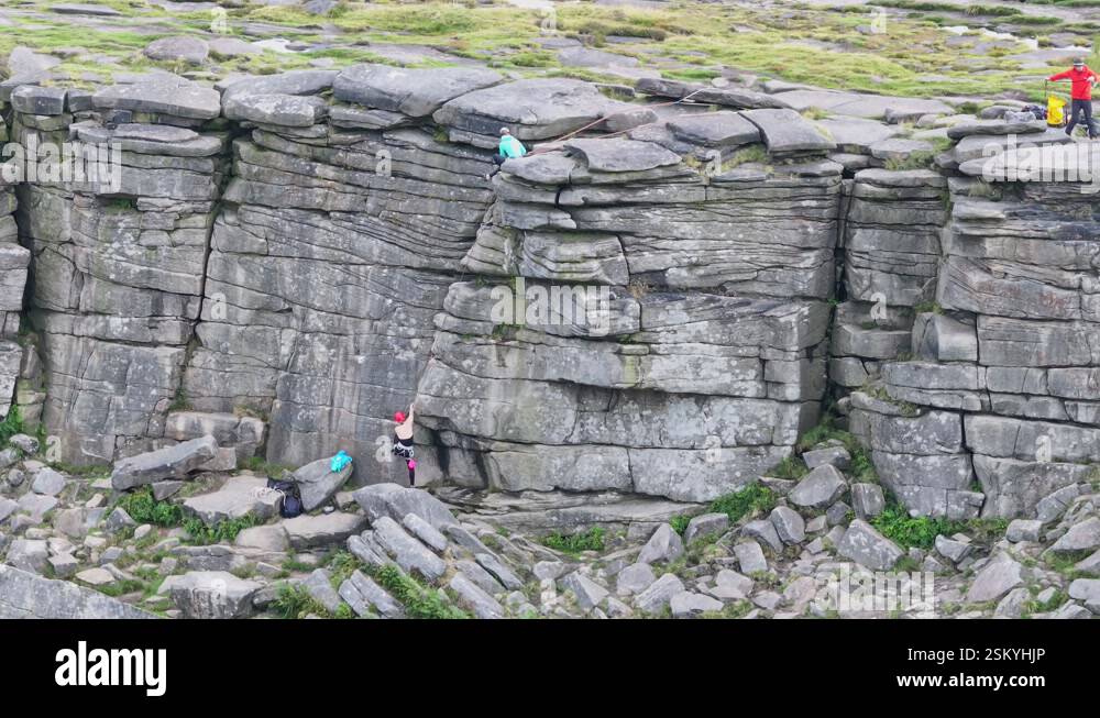 Climber sits at top of route belaying top rope climber along route at ...