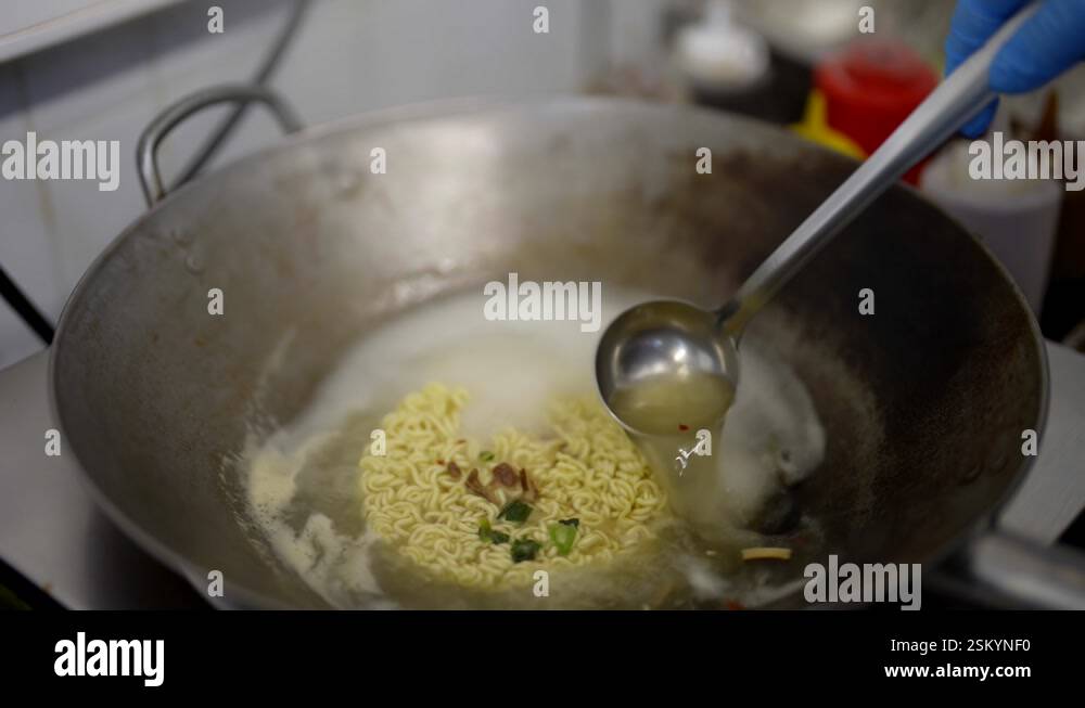 A professional chef cooks noodles. The cooking process is a close-up ...