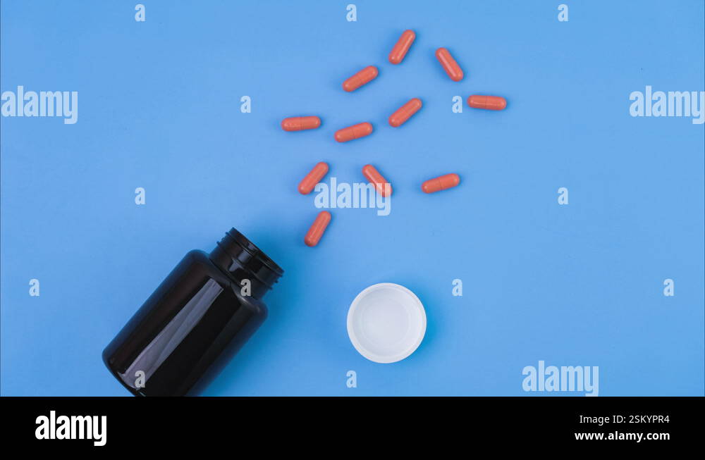 Pill capsule pouring from pharmacy bottle on blue background Stock ...