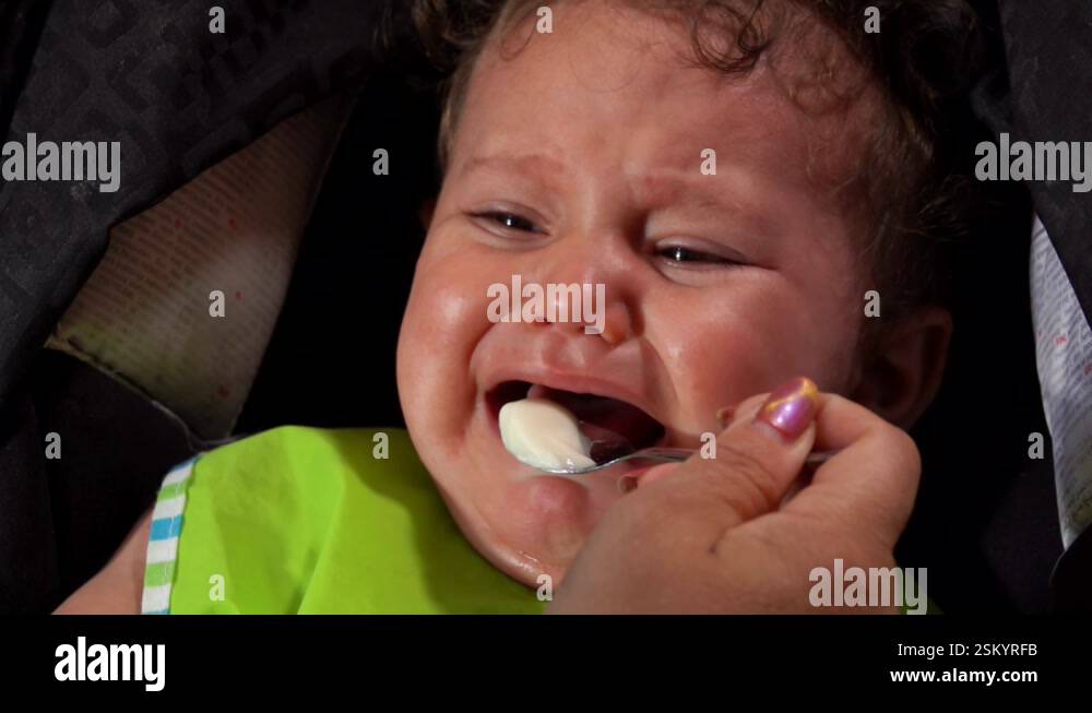 Curly brown-eyed baby boy is crying and refusing to eat mashed ...
