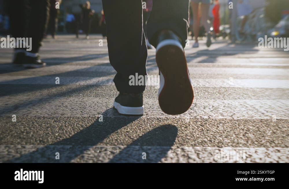 Rear view follow male feet steps crossing city street. People crowd ...