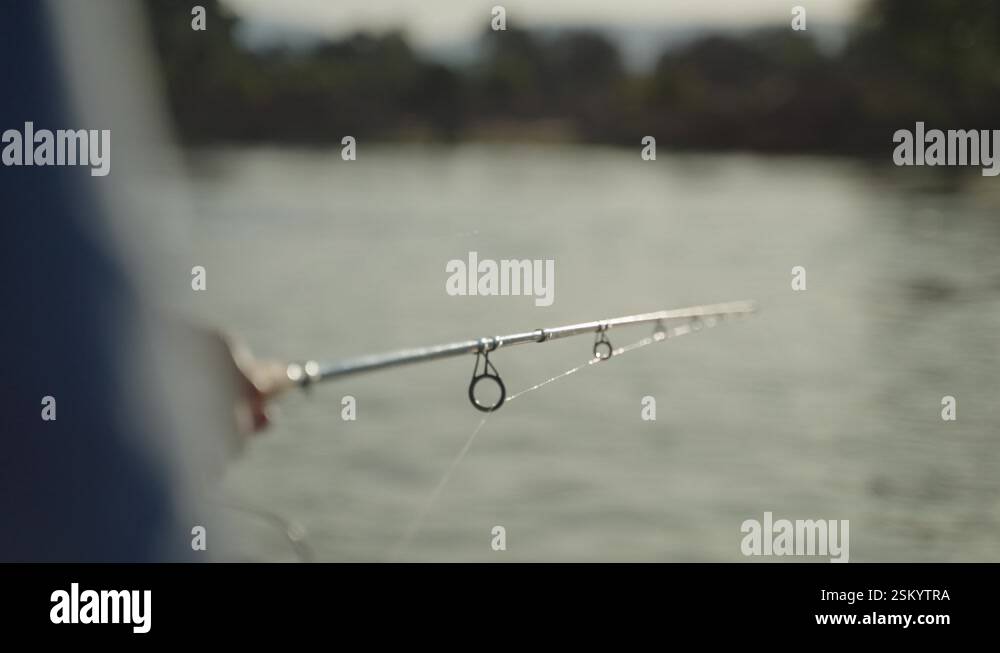 A man fishing on the riverbanks of with an elephant in the distance on ...