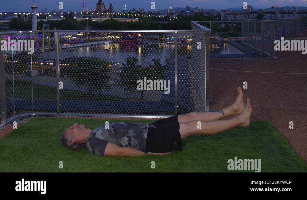Cool guy is doing Flutter Kicks in the evening on a modern terrace with ...