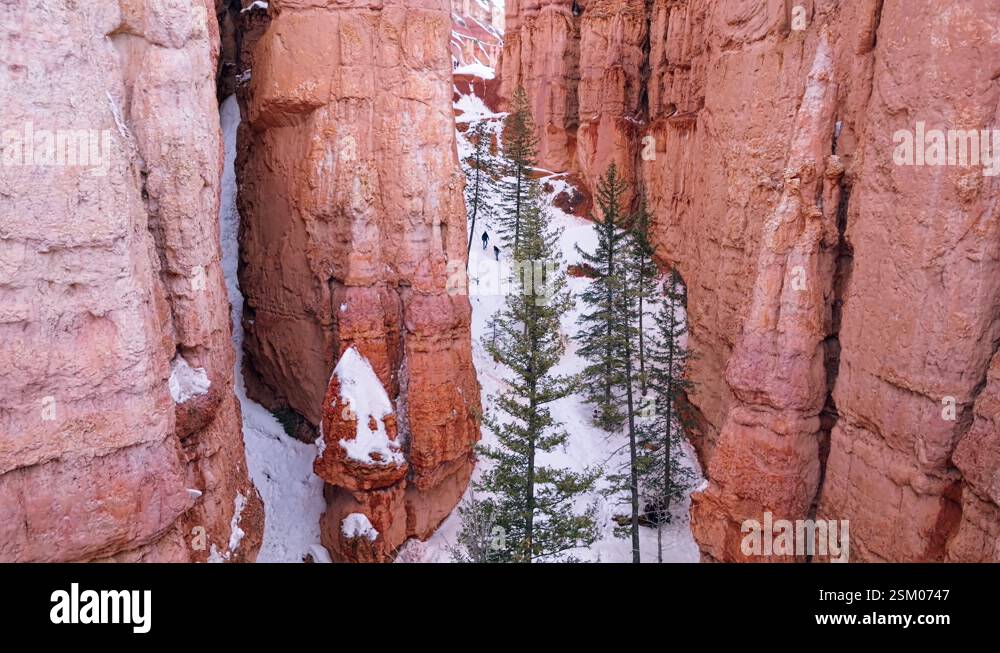 Hikers Walking On Snow-Covered Ground Between Spire Rock Formations In ...