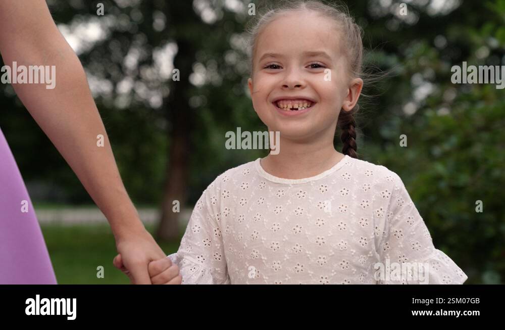 Pretty little daughter without milk teeth smiles holding mother hand in ...