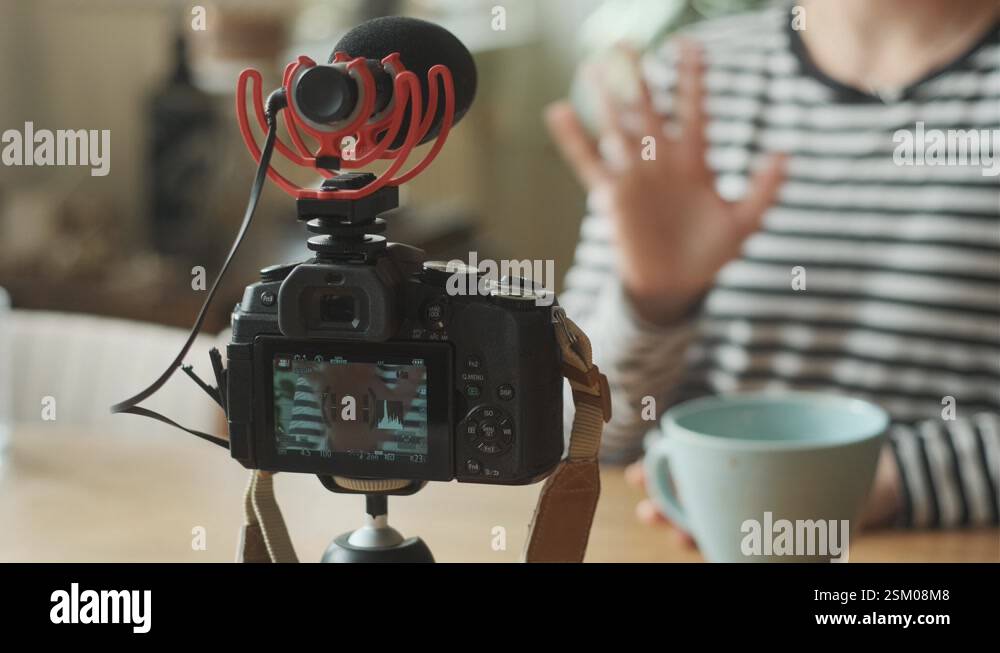 Female sitting in front of camera and recording video inside apartment ...