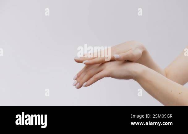A young woman applies moisturizer to her hands, showing her commitment ...