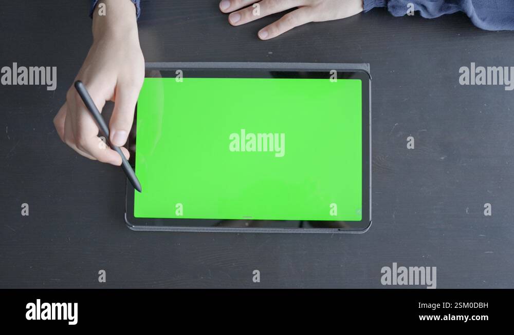Green screen tablet lays flat on black desk, female hands indicating ...
