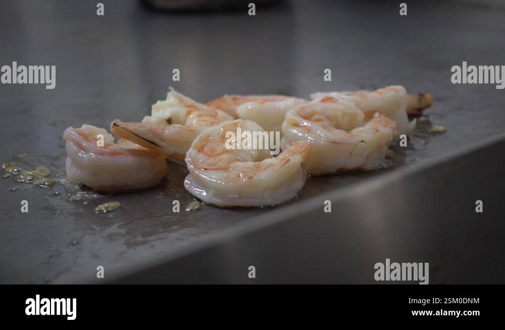 Close-up shot of raw shrimp cooking and bubbling on an open cooker ...