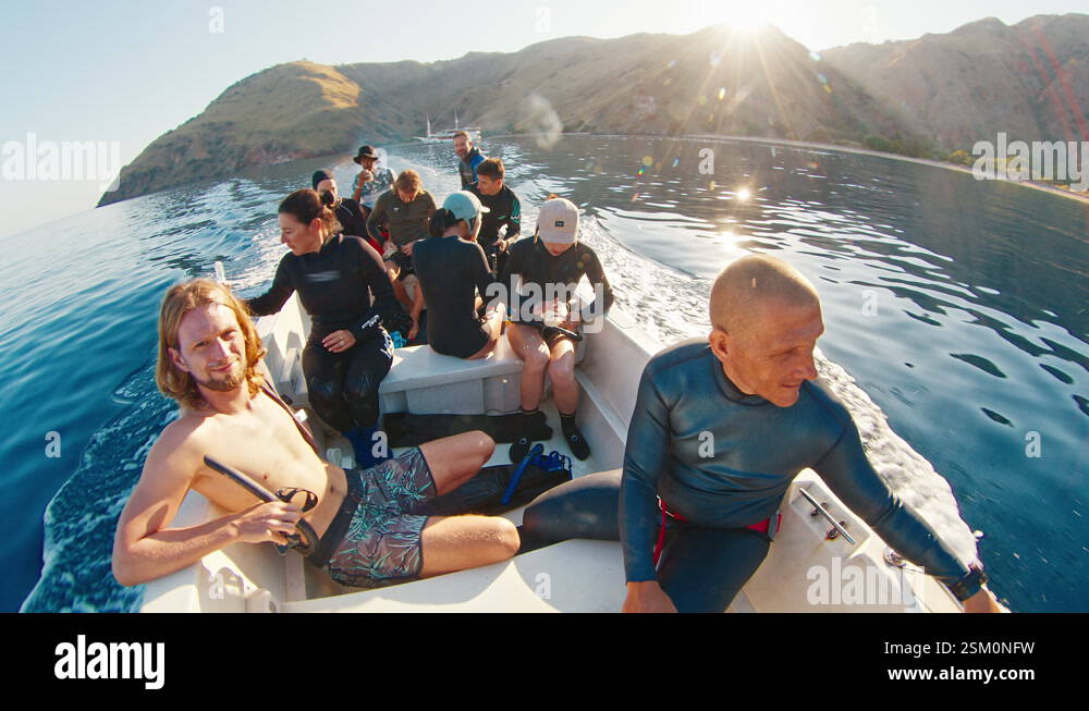 Group of freedivers in wetsuits sit in the small transfer boat and move ...