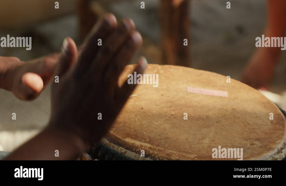 Close-up of an African man passionately playing a bongo with his hands ...