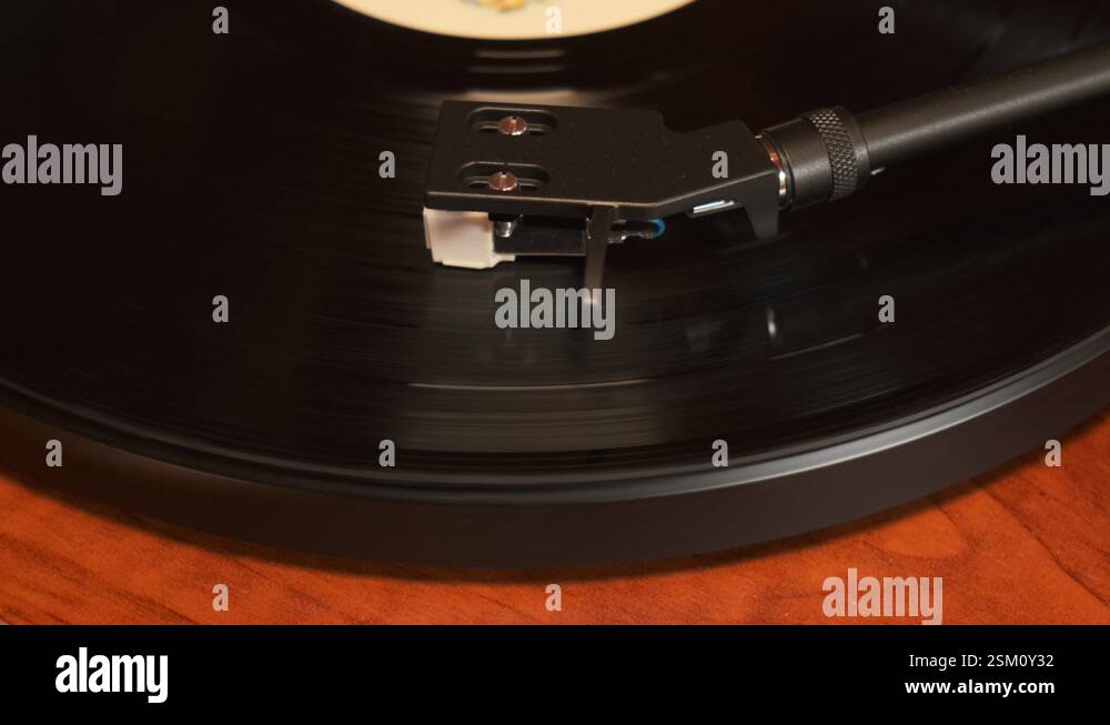 Close up view of a turntable tonearm with platter spinning, slow motion ...