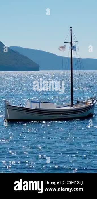 Traditional fishing boat in the Aegean sea with greek flag, Milos ...
