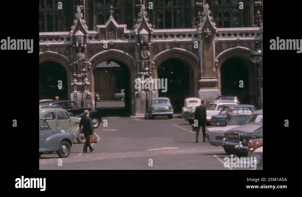 1960s: Ornate stone carved arches with statues in street. Cars parked ...