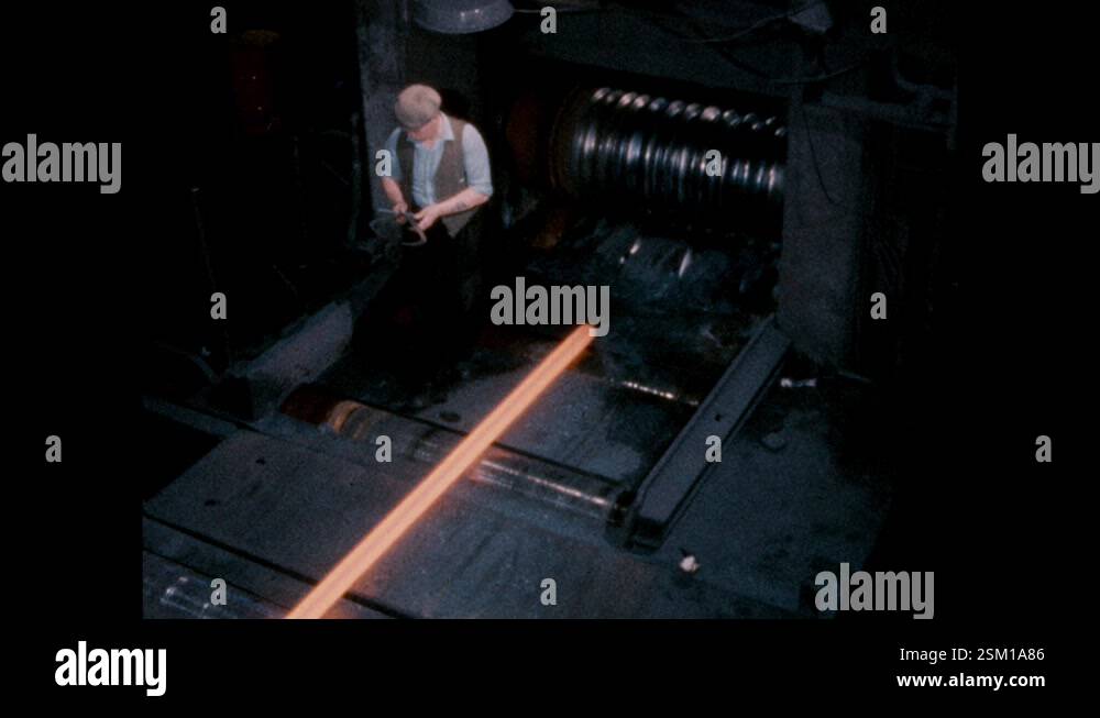 1960s: Length of molten metal in rod shape rolls out of furnace Stock ...