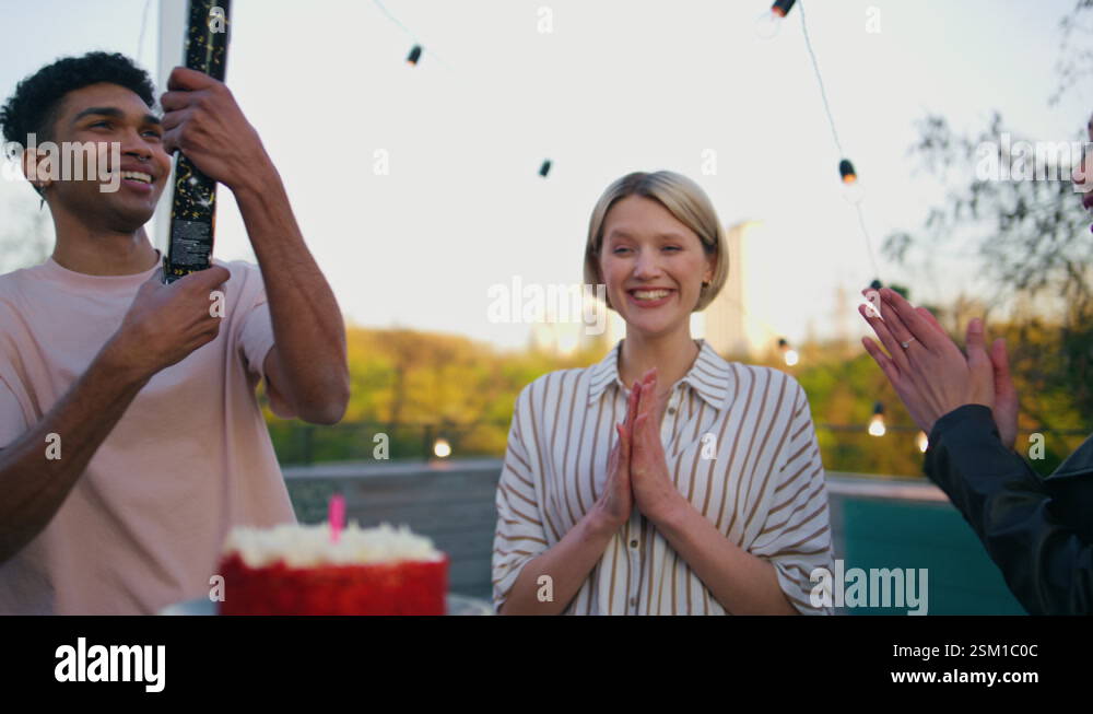 Birthday girl blowing cake candles on rooftop party closeup. Friends ...