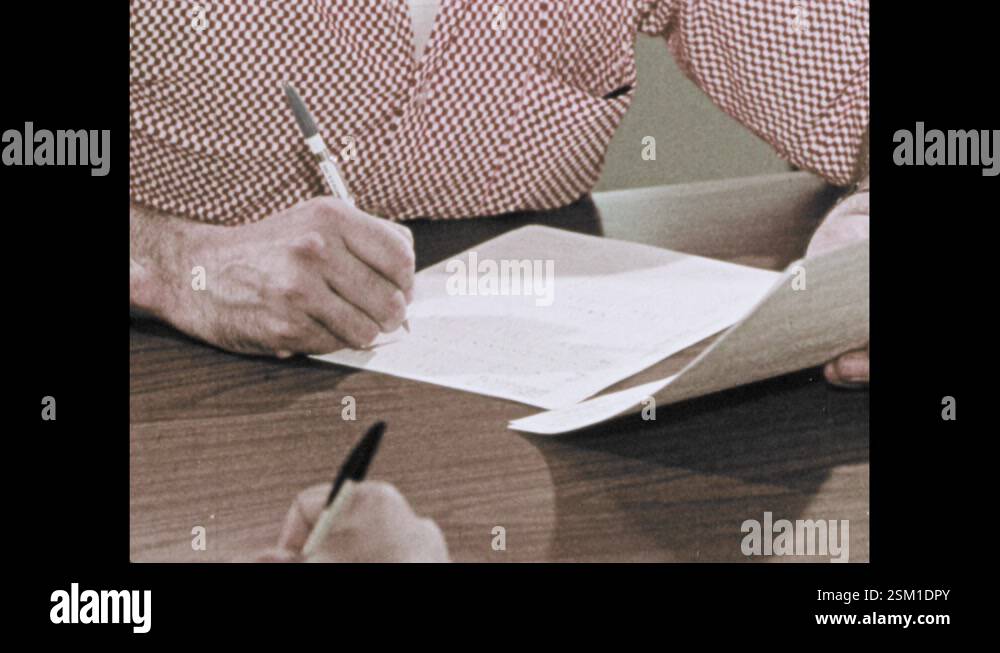 1970s: Men write in office building. Man and woman talk on path of ...