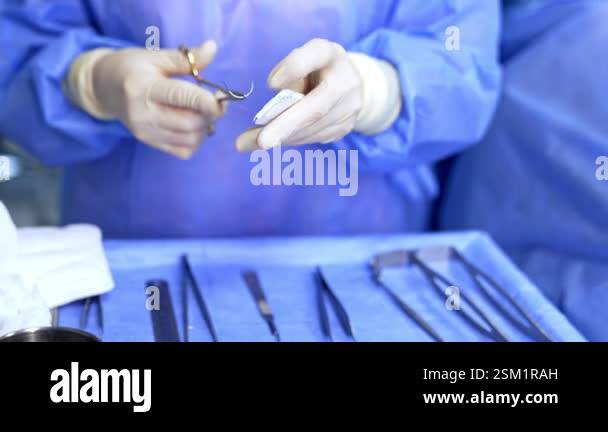 Unrecognized scrub nurse arranges tools on the surgical stand. Medic ...