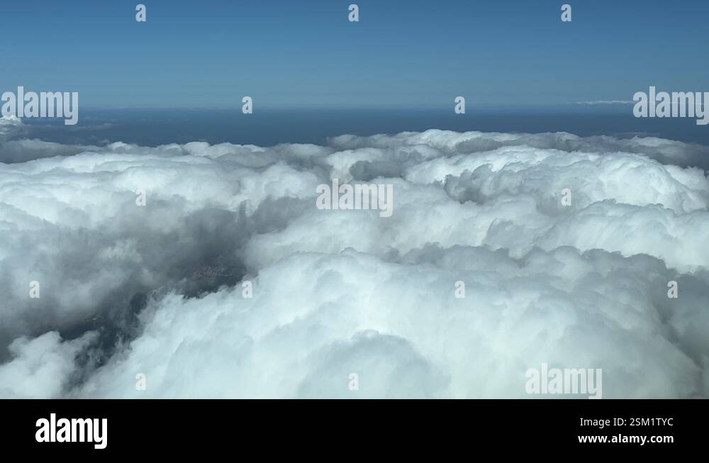 Overflying some fluffy clouds during cruise, shot from a jet cabin at ...