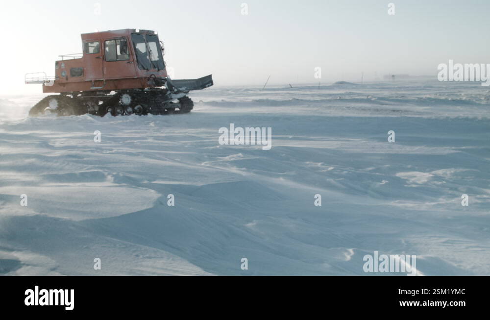 Tracking shot of Tucker-Terra Track Vehicle driving on snowy road in ...