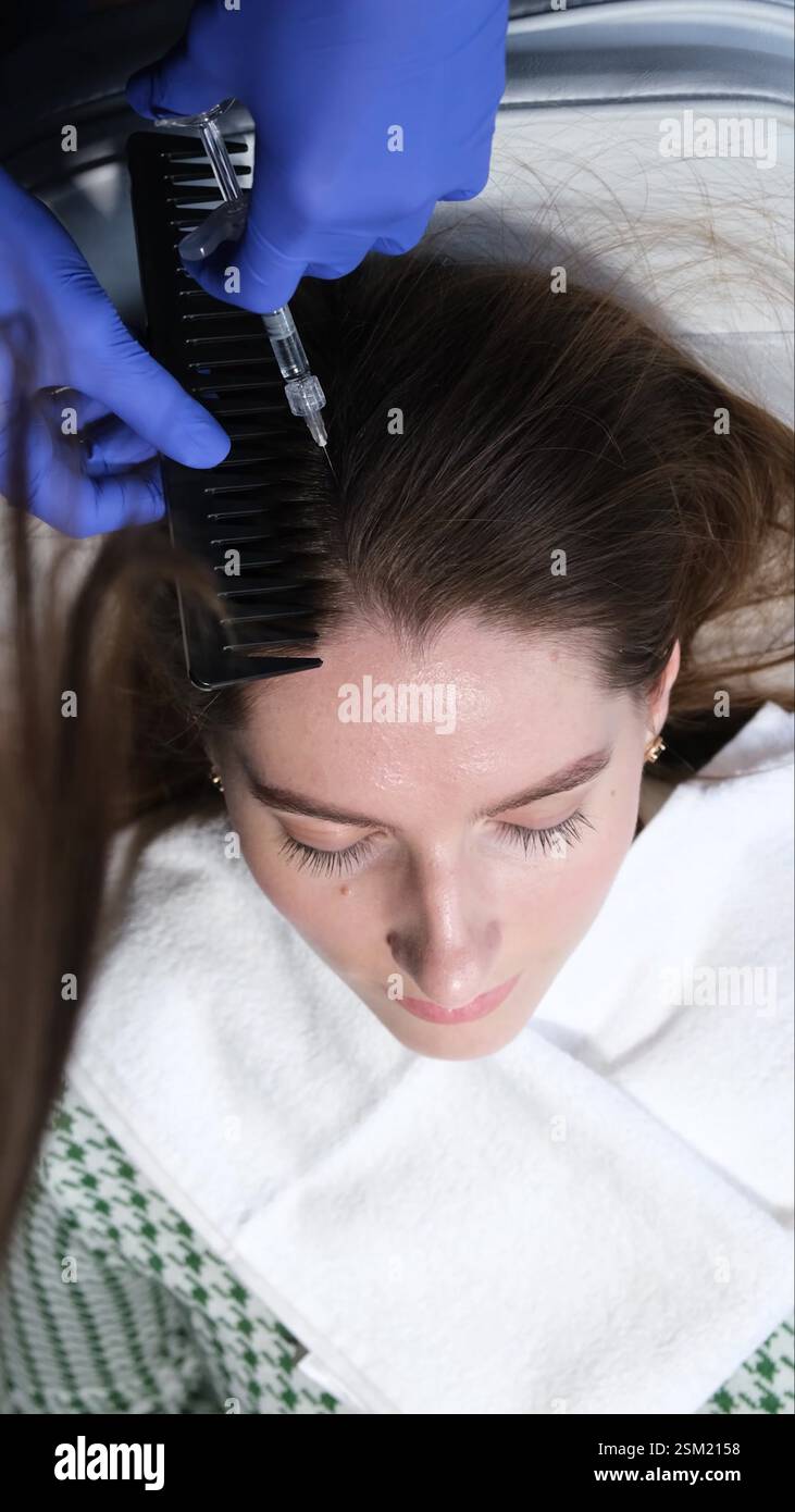 A young woman receives hair mesotherapy injections from a professional ...