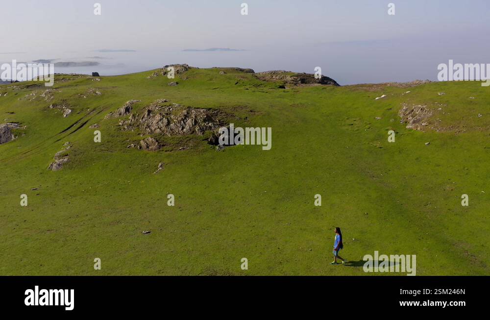 Man walking on a grassy island. Wide angle reveals the magnificent view ...