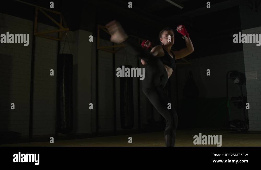 Young woman fighter trains his kicks in the boxing gym, front view, 4k ...