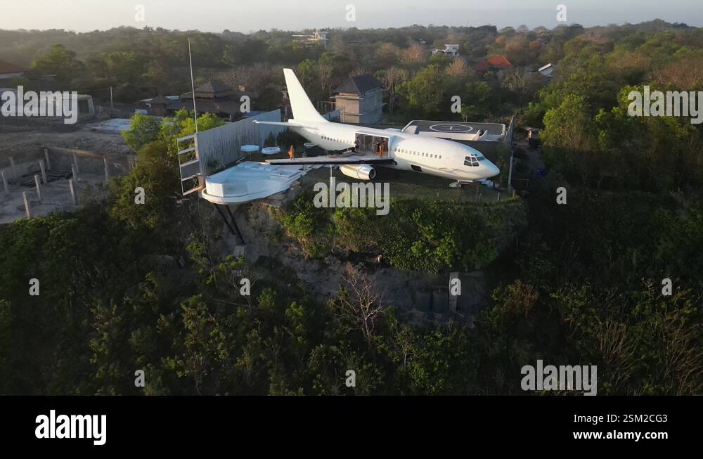 Aerial: Tourist poses on wing of jet overhanging Bali jungle cliff ...