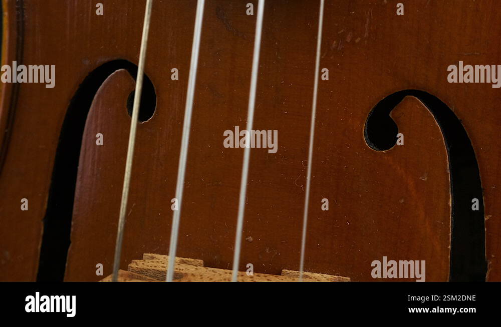 Extreme close up view of violin body, F holes rotating in dark room ...