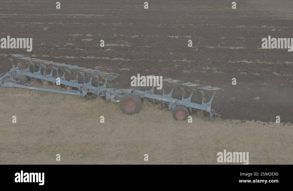 Hi productive reverse plow moving behind a tractor in an field. Plowing ...