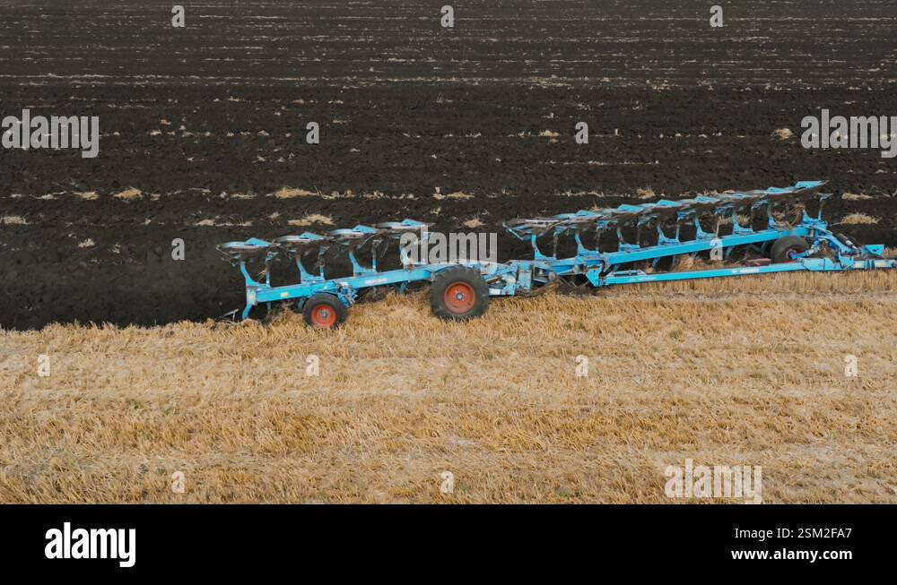 Reversible plow on support wheels moving behind a tractor in an field ...