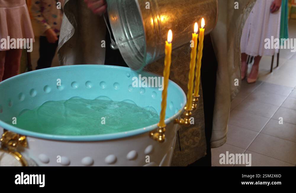 water from a bucket is poured into the baptismal font in the Orthodox ...
