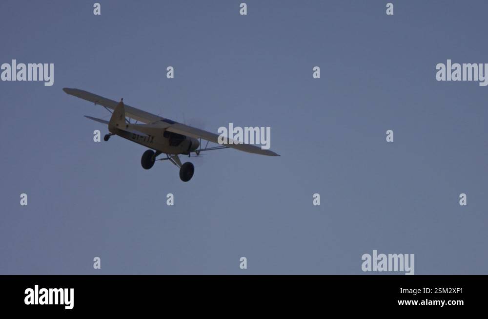 Low angle pan of Super Cub plane making a right turn while flying at ...