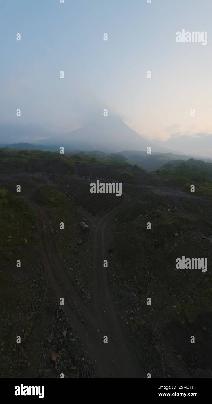 Vertical video. Tropical dirt road canyon frozen volcanic lava smoke ...