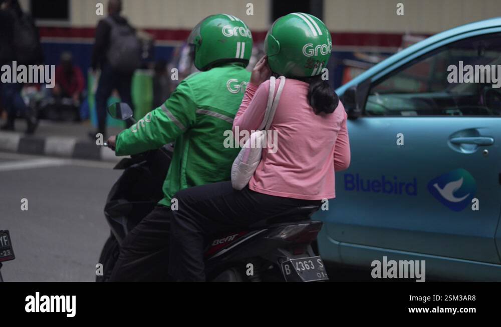 Grab driver with female passenger on the road next to bluebird taxi in ...