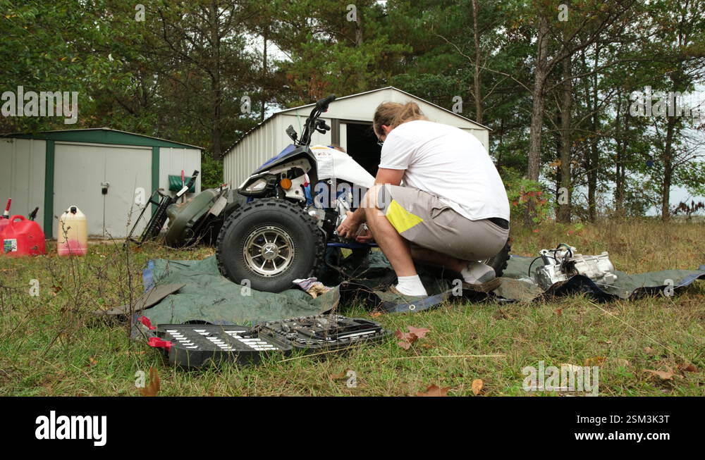Two men installing new gas motor into four wheeler or ATV after old ...