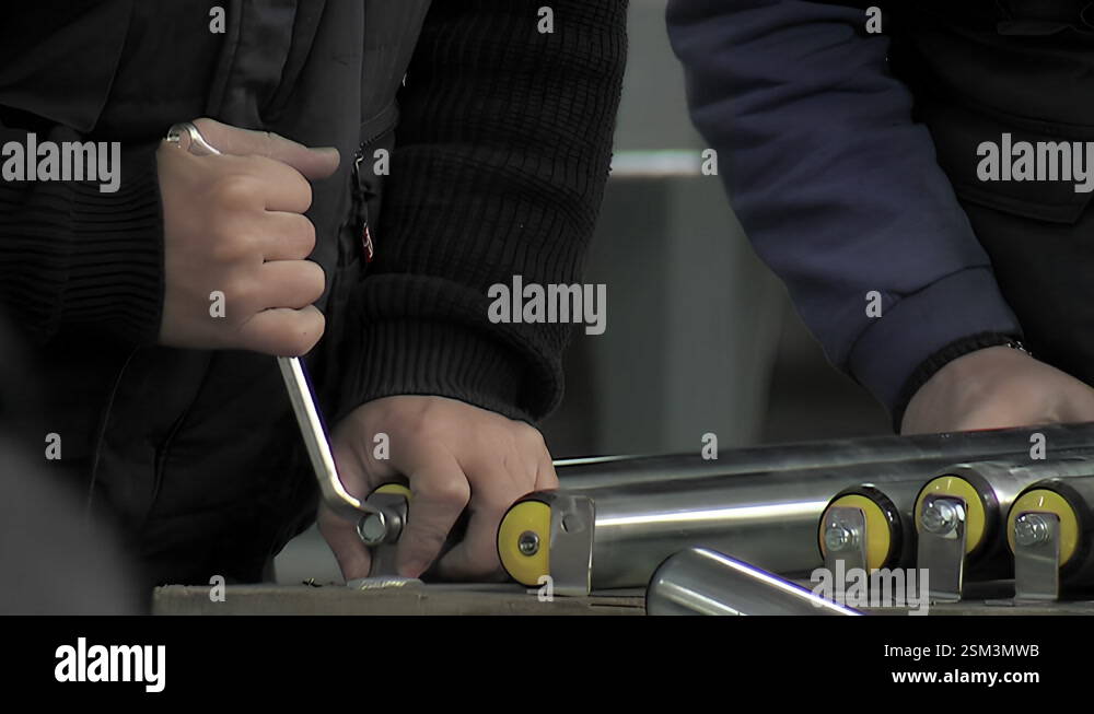 Operator tightening a roller on an industrial food processing line with ...