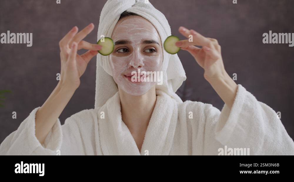 Woman in bathrobe using facial mask for cleansing and cover eyes with ...
